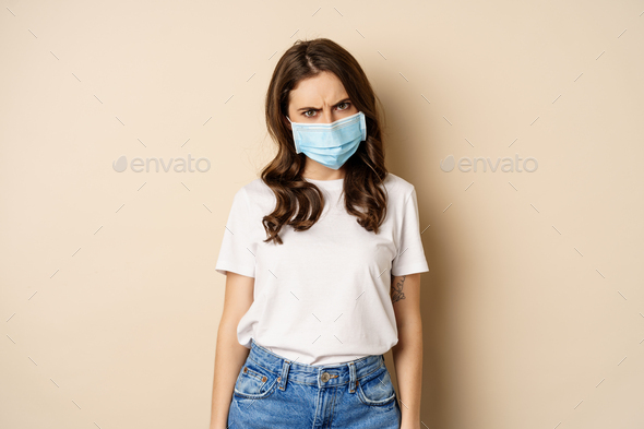 Image of angry girl in medical face mask, grimacing and looking ...