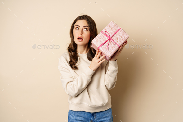 Excited cute girl shaking box with gift, guessing whats inside present ...