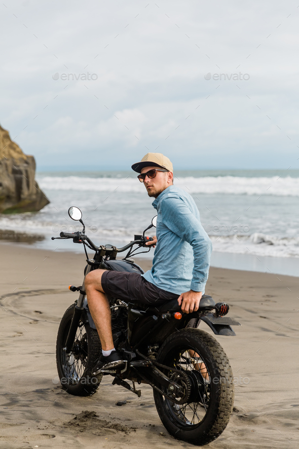 Man in cap riding motorcycle on beach. Moto cross dirtbiker on beach ...