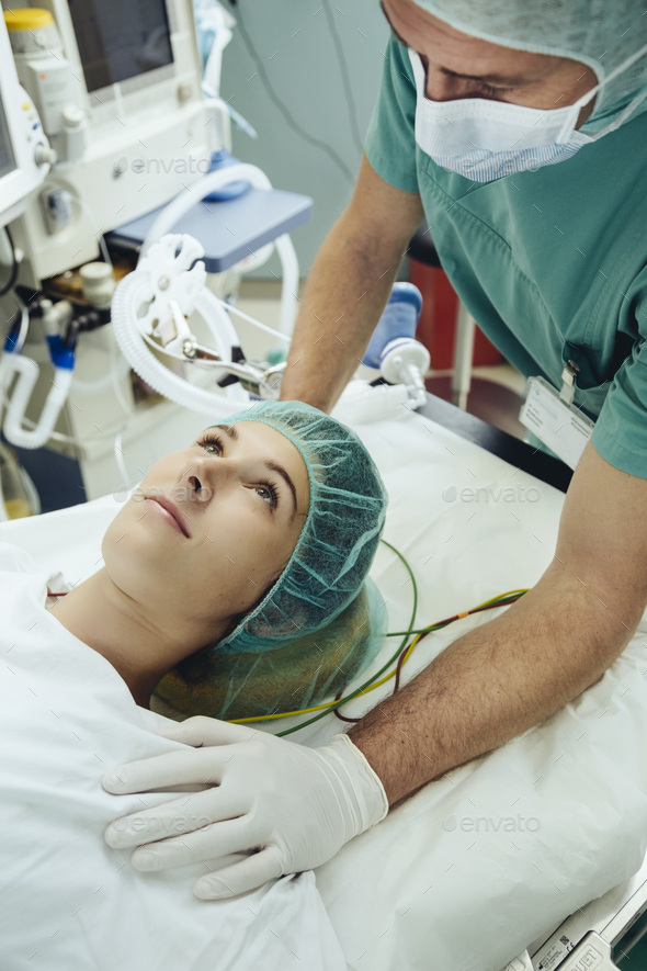 Operating nurse soothing patient on table in operating room Stock Photo ...