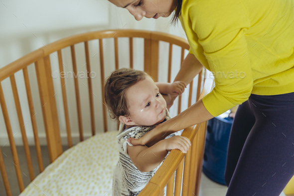 Mother picking up her baby girl from bed Stock Photo by westend61 ...