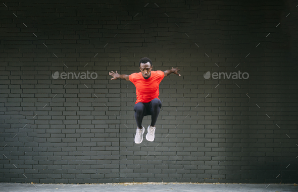 Young sportive man jumping in front of a brick wall Stock Photo by ...