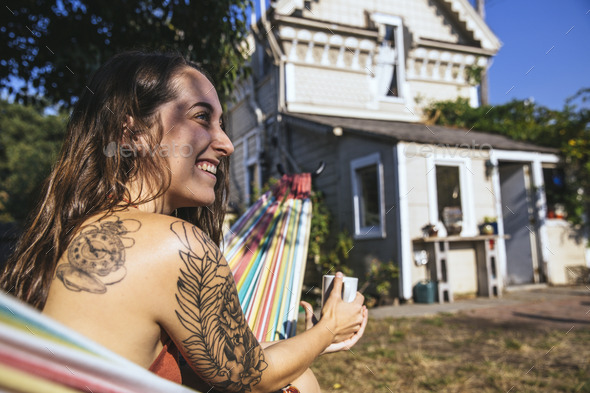 Happy young woman with tattoo in hammock Stock Photo by westend61 ...