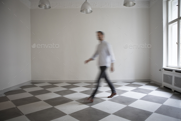 Man crossing empty room of an apartment Stock Photo by westend61 ...