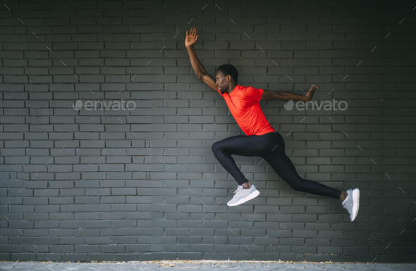 Young sportive man jumping in front of a brick wall Stock Photo by ...