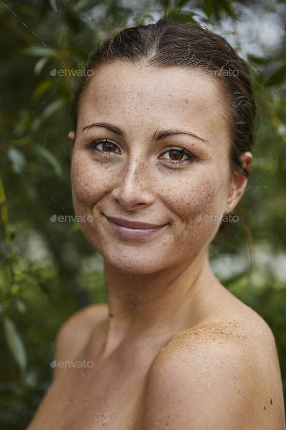 Portrait of freckled young woman in nature Stock Photo by westend61