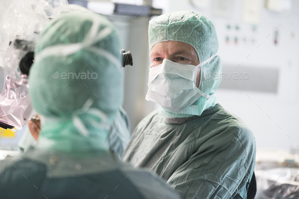 Neurosurgeon consulting colleague during an operation Stock Photo by ...