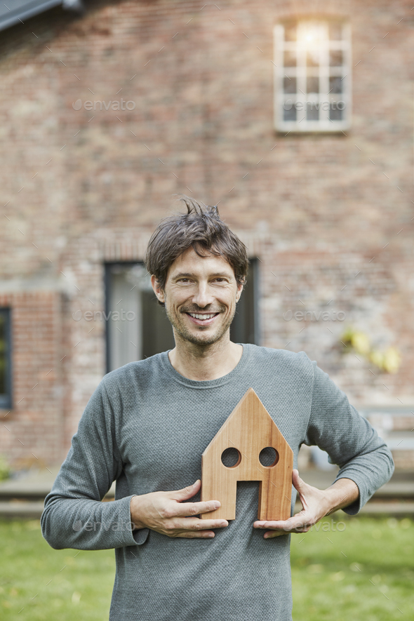 Portrait of smiling man in front of his home holding house model Stock ...