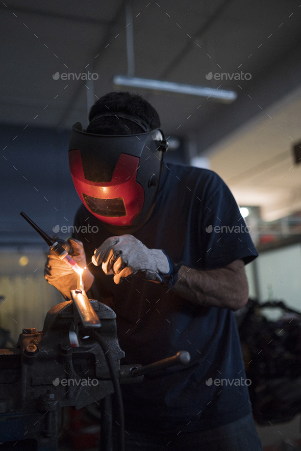 Mechanic in a repair garage welding Stock Photo by westend61 | PhotoDune