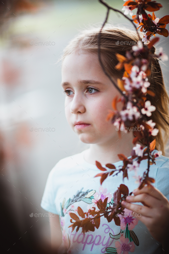 Outdoor portrait of happy child girl in spring park, cherry trees in ...