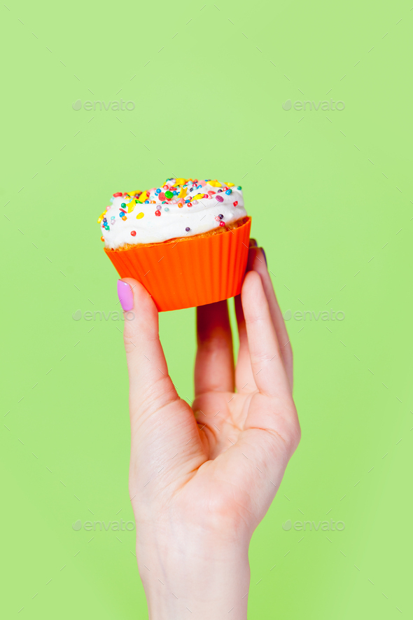 photo of female hand holding cupcake on the wonderful green background ...