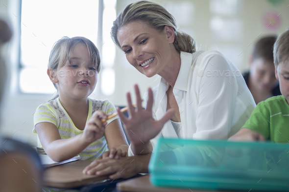 Schoolgirl counting teacher's fingers in classroom Stock Photo by westend61