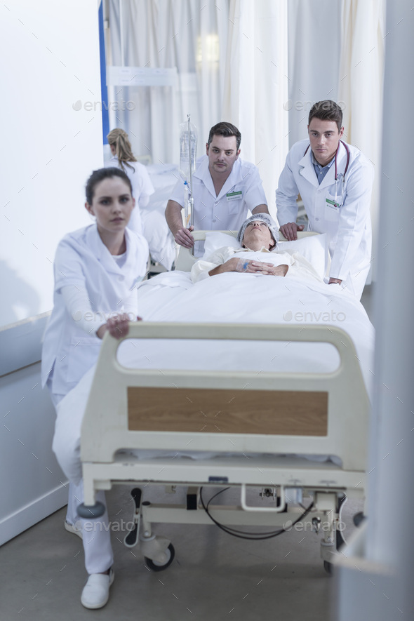 Hospital staff pushing bed with patient on floor Stock Photo by westend61