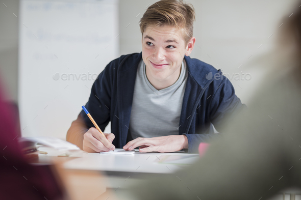 Smiling teenage boy taking notes in class Stock Photo by westend61