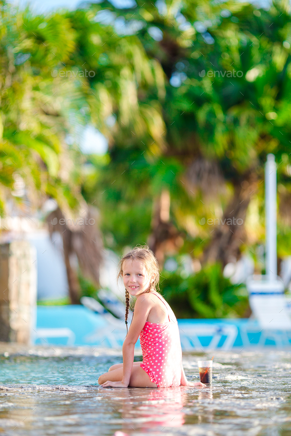 Little girl in outdoor swimming pool enjoy her vacation with tasty ...