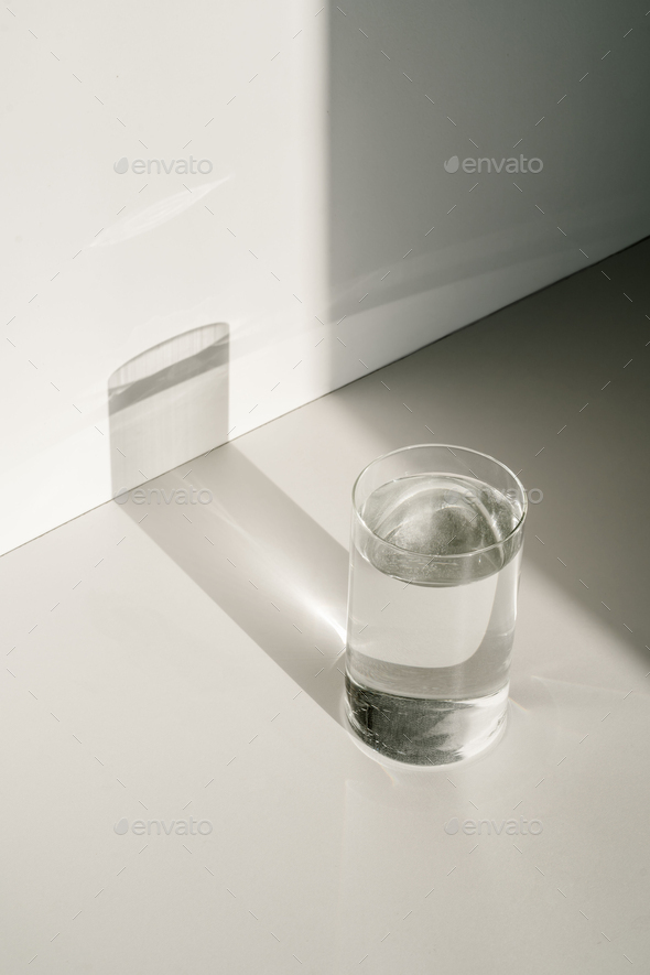 Transparent glass of water in the sunlight on a white background Stock ...