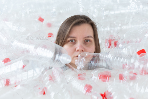 Dehydrated sick woman is lying in a pile of plastic bottles ...