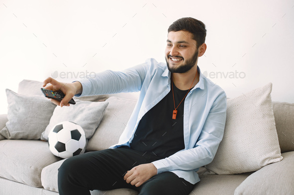 Brunette guy sitting on a coach and watching football at home Stock ...