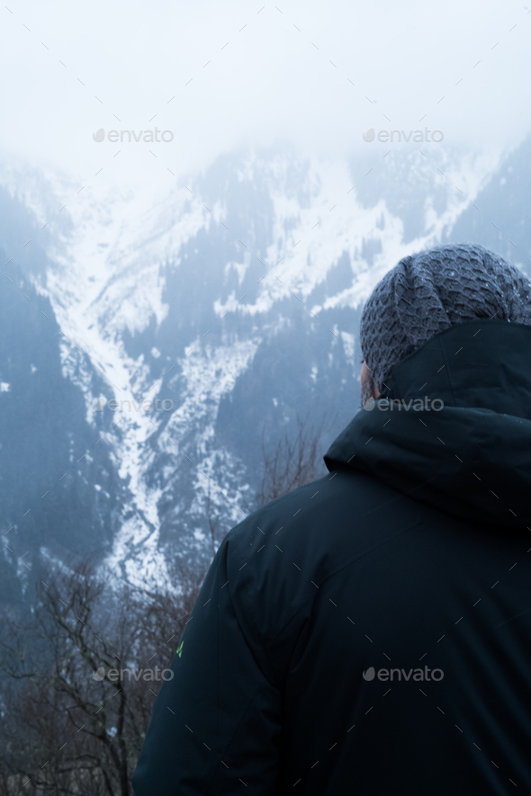 Turkey, Rear view of man facing mountain covered with snow and fog ...