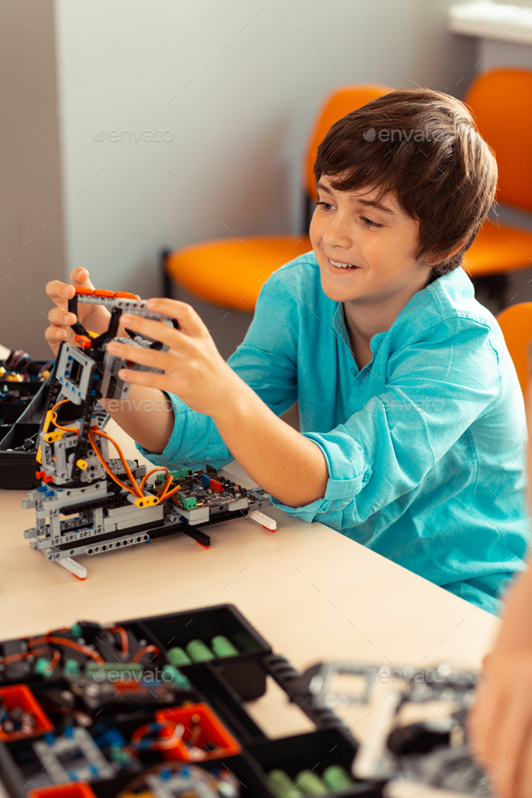 Cheerful boy playing with the robot he built Stock Photo by Iakobchuk