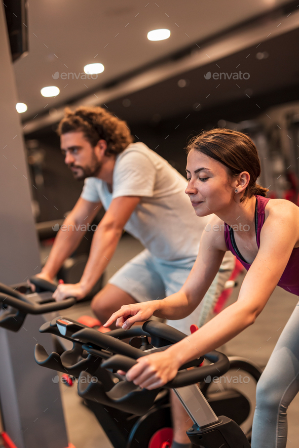 People cycling on gym bike machines Stock Photo by Impactphotography