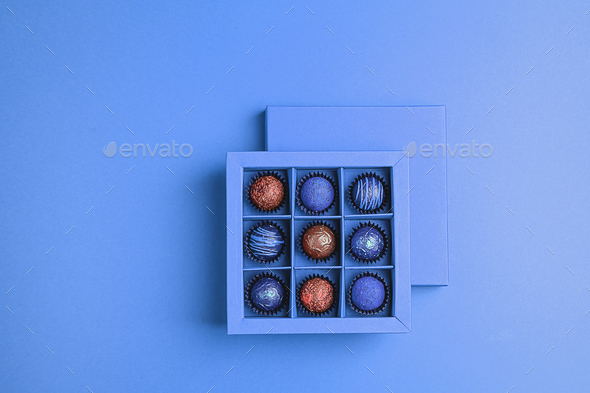 Handmade chocolates blue box neon blue background. Flat top view ...