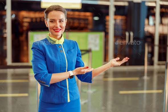 Cheerful female flight attendant pointing at something at airport Stock ...