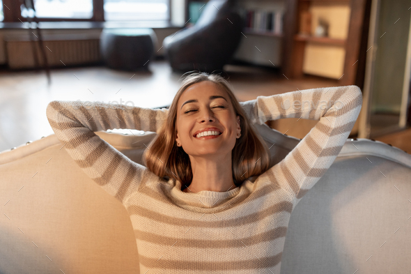 Calm woman having rest at home on the couch Stock Photo by Prostock-studio