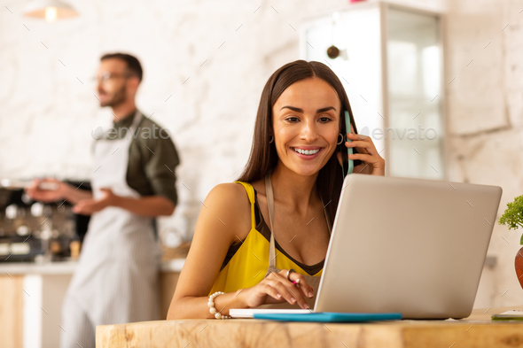 Female entrepreneur sitting near laptop while ordering foods Stock ...