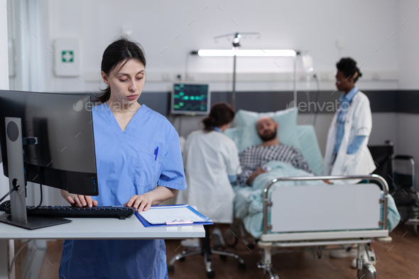 Nurse using personal computer to complete patient admission chart while ...