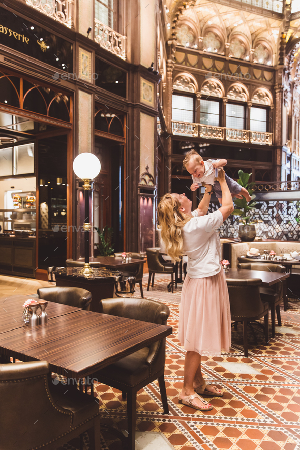 Beautiful woman in a white dress with her son has a rest in the cafe in ...