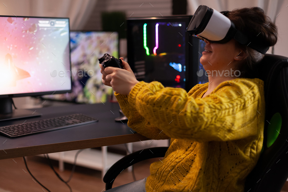 Woman gamer wearing virtual reality goggles holding joystick playing ...