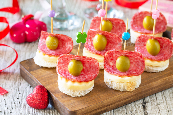 Canapes with bread, cheese, salami and olives. Stock Photo by khramovaelena