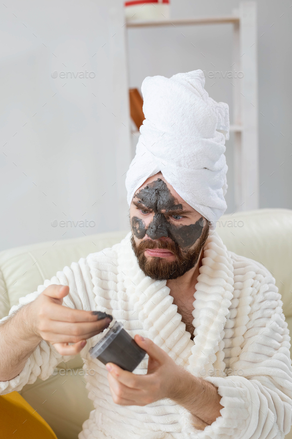 Bearded funny man having fun with a cosmetic mask on his face made from ...