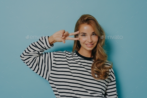 Horizontal shot of pleased lovely young woman with long hair shows ...