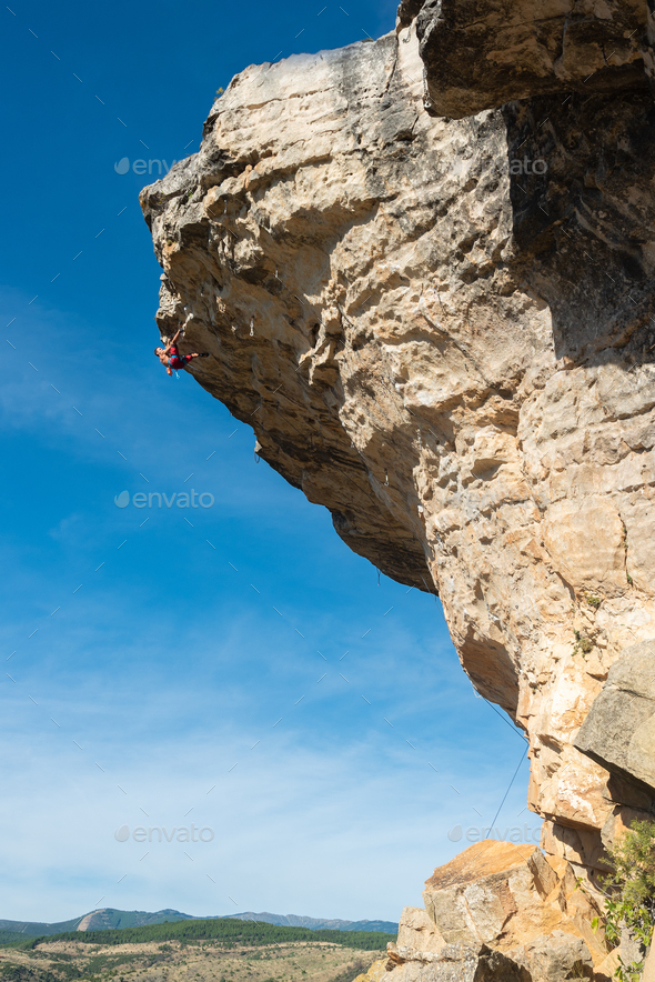 Distant view of a rock climber hanging and climber a rock formation ...