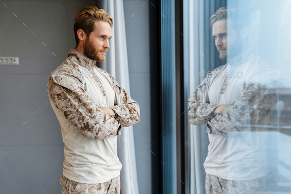 Masculine confident military man standing and looking out window ...