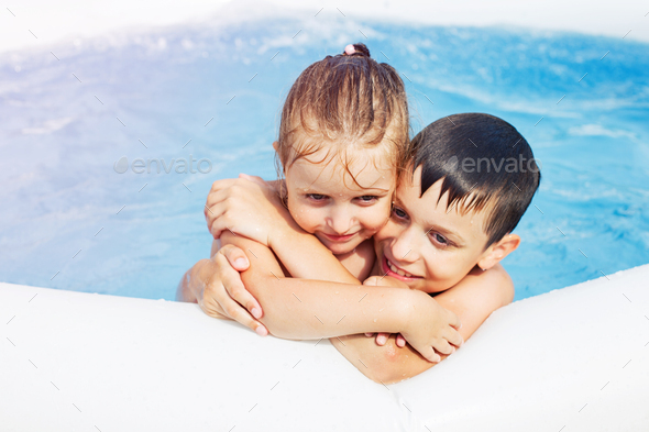 portrait of happy boy and girl in the pool in the garden at summer ...