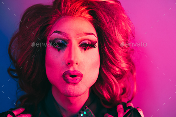 Drag queen looking at camera with neon color lights inside studio ...
