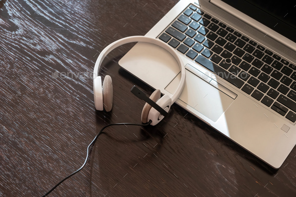 Headset on a laptop, wooden table. Call center, home office, customer ...