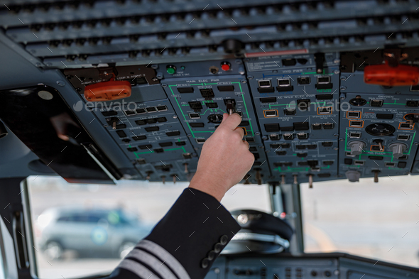 Aircraft pilot operating overhead panel of airplane flight deck Stock ...