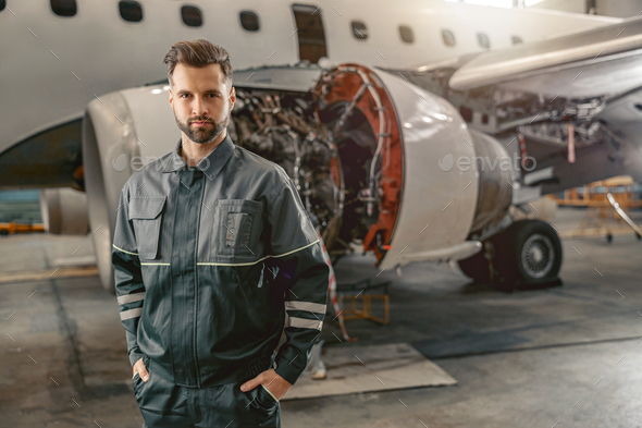 Male airline mechanic standing near aircraft in hangar Stock Photo by ...