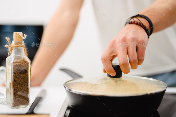 Young white man using frying pan while cooking in kitchen Stock Photo ...