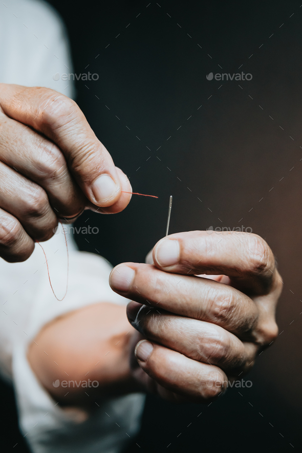 Close up on woman's hands sewing needle and thread. Old woman working ...