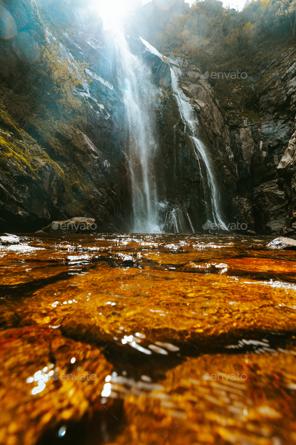 Massive waterfall over some rocks during a super sunny day Stock Photo ...