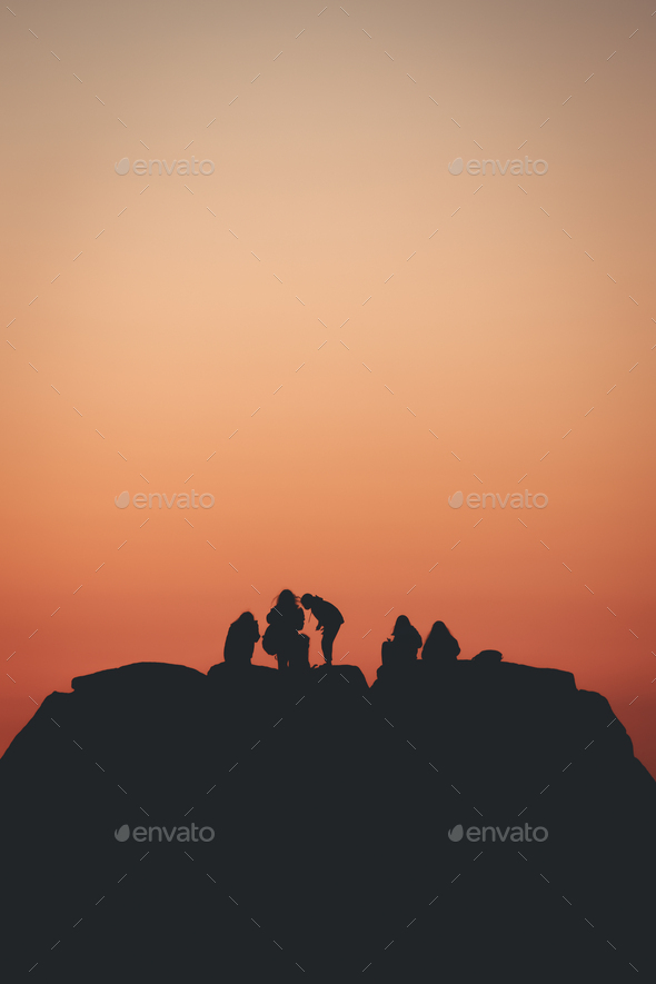 Silhouette of a group of friends over a colorful sunset during a sunny ...