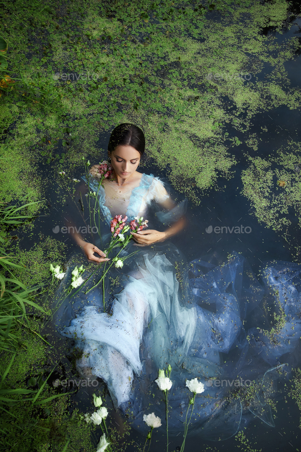 Art beautiful romantic woman lies in swamp in blue long dress with ...