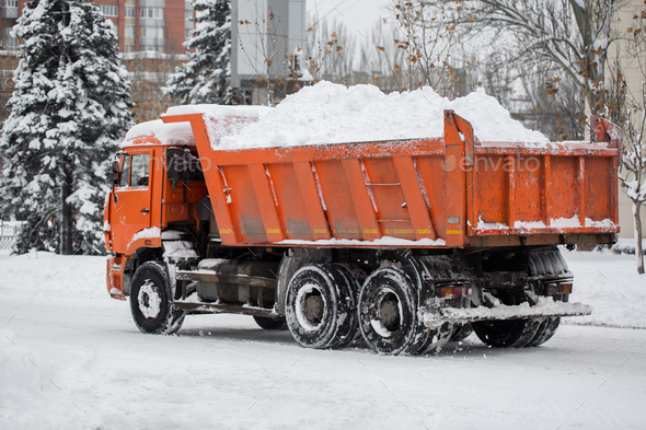 Dump truck full of snow driving through city street, snow hauling. Dump ...