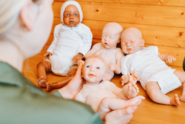Back view of young woman holding realistic cute doll of newborn ...