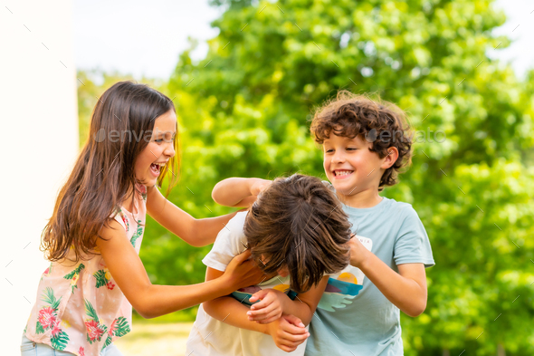 Lifestyle of three brothers smiling and playing together in a park ...